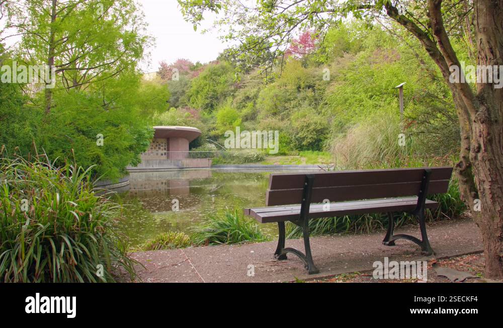 Old park bench by stream surrounded by greenery. Souvenirs gardens ...
