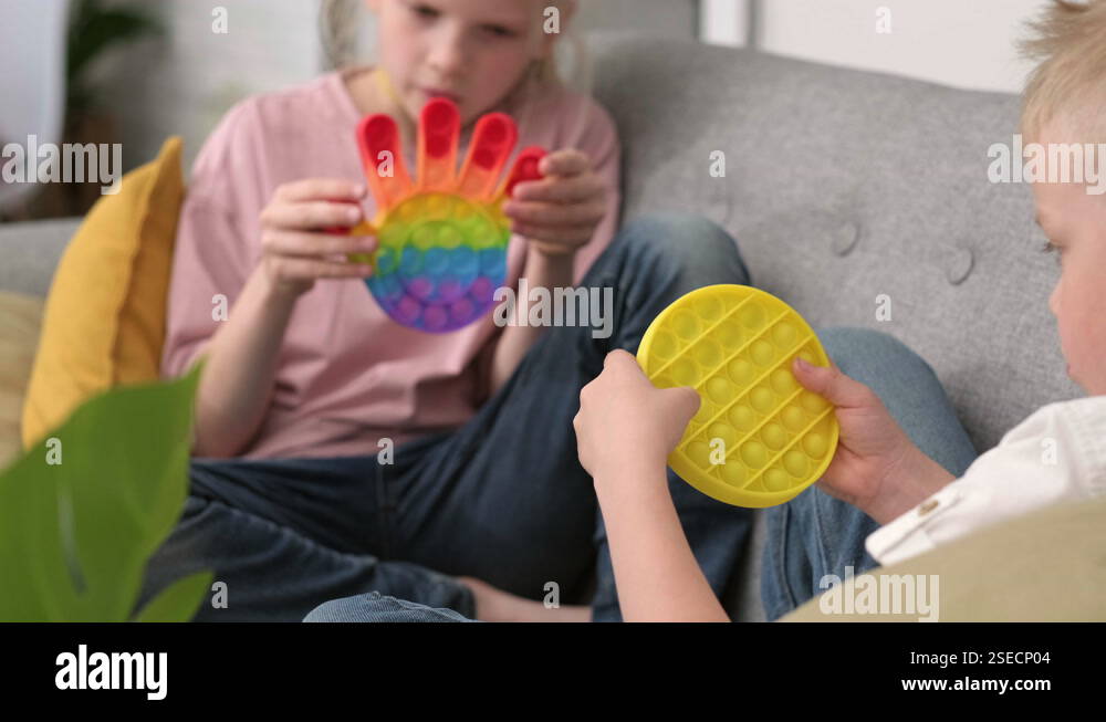 Kids playing with pop it sensory toy. boy and girl pressing on colorful ...