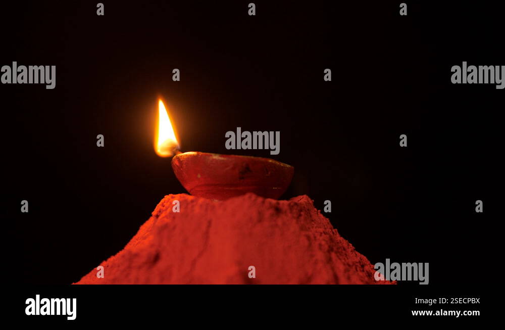 A lighted earthen oil lamp on a heap of powder color - Diwali rangoli ...