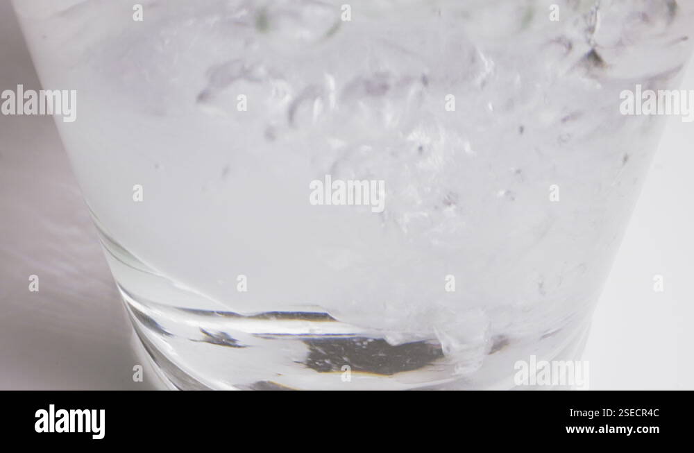 Ice cubes and bubbles float in sparkling water in glass Stock Video Footage - Alamy