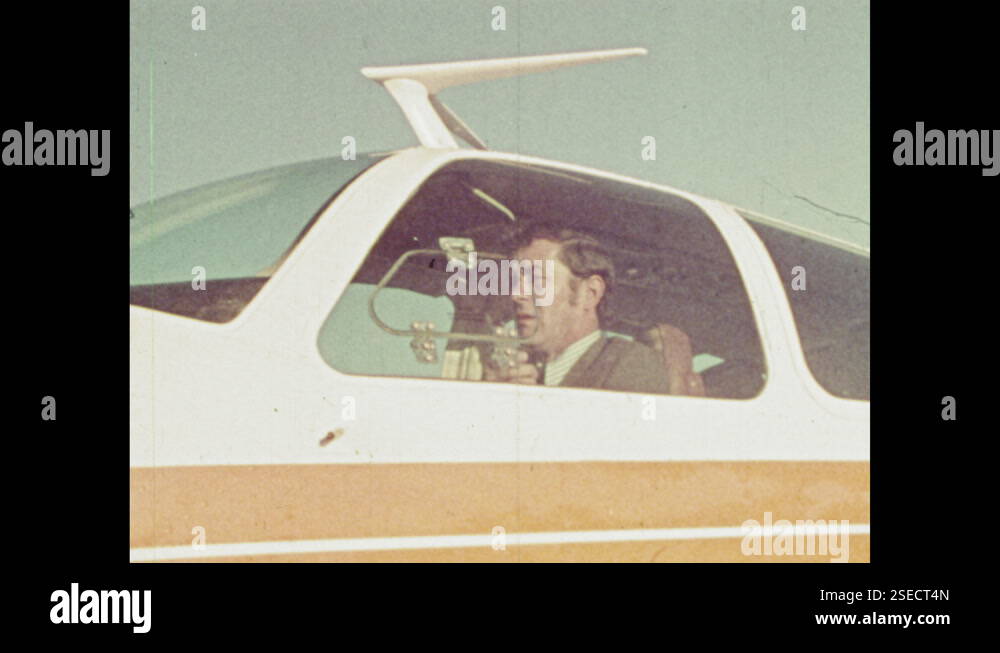 1970s: Man flying plane, talking into radio. View from underside of ...