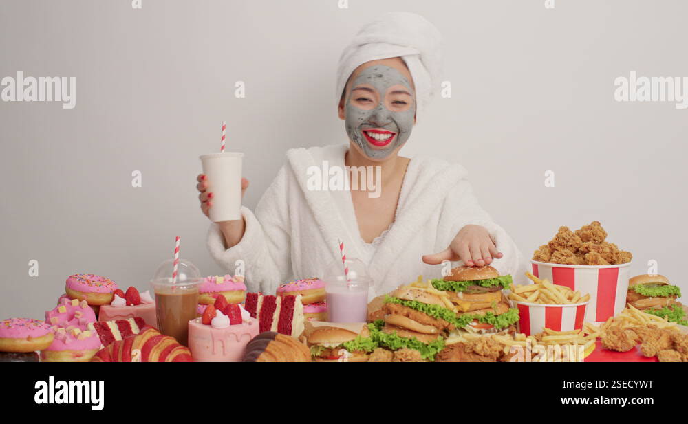 Funny Asian woman foolishes around eats fast food dances carefree ...