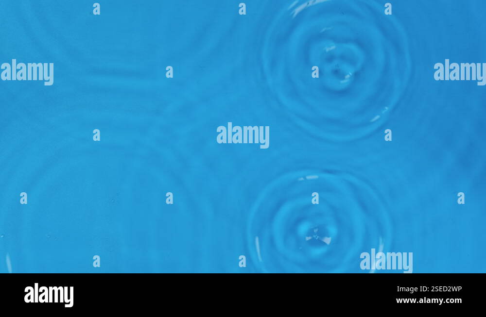 Slow motion. Four drops falling into clear, transparent blue water ...