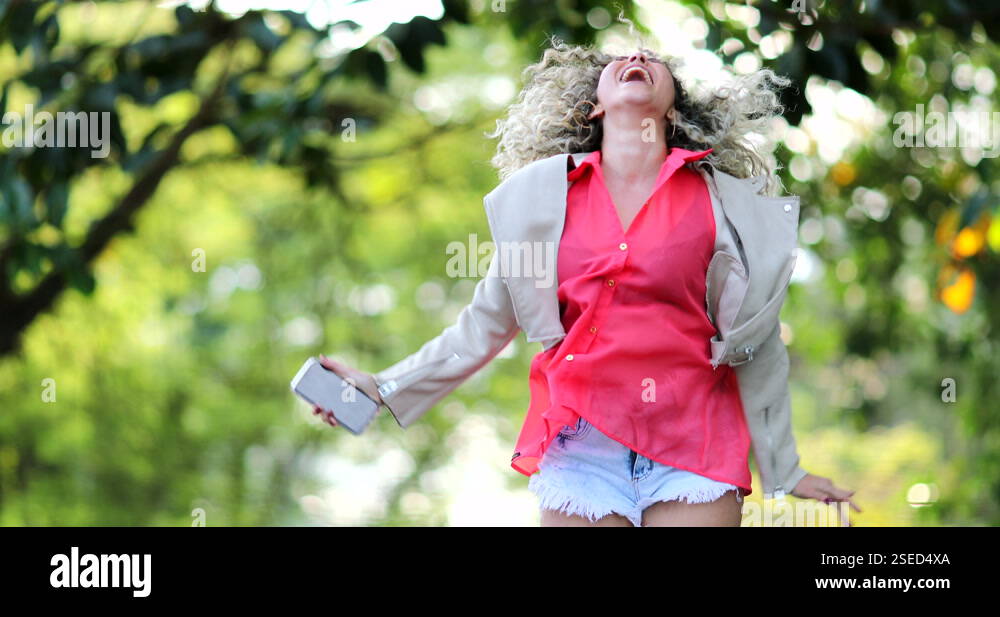Ecstatic woman receiving confirmation message on cellphone jumping with ...
