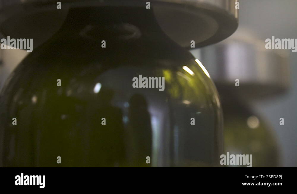 Slow motion, close-up pour wine into a bottle, on the conveyor belt ...