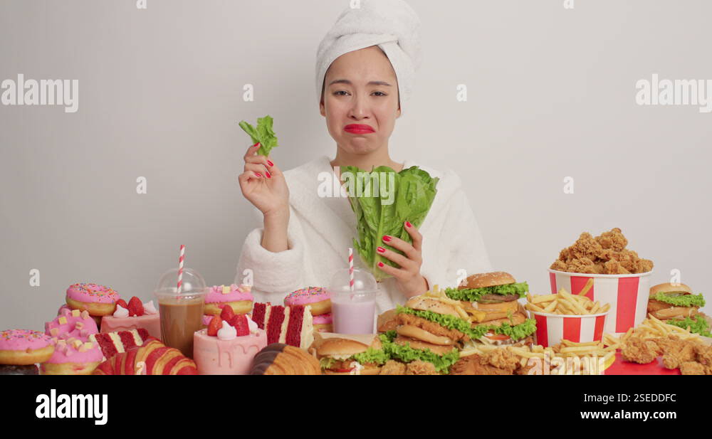 Young Asian woman tries to eat only healthy food consumes green salad ...