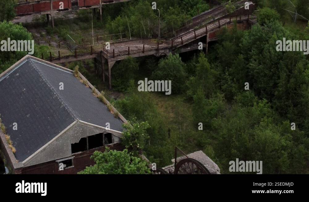 Abandoned old overgrown coal mine industrial rusting pit wheel aerial ...