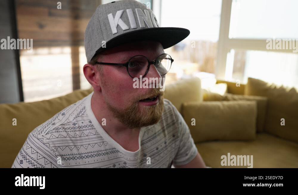 Man watching television, opens mouth in shock, laughs, slow motion zoom ...
