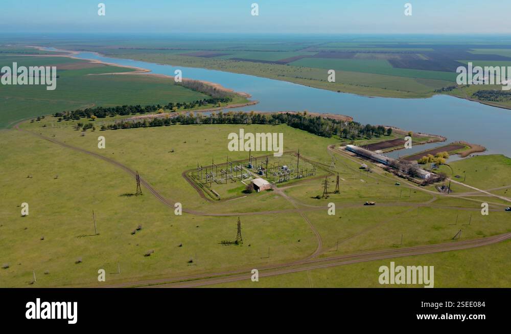 Hydroelectric power stations on river bank and passing tractor with ...