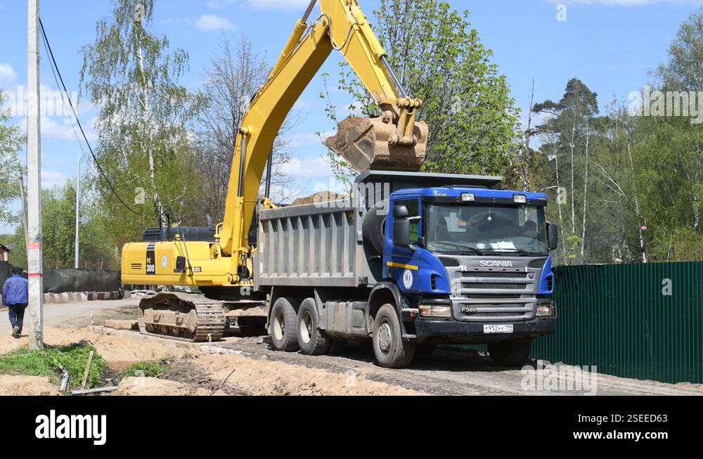 Excavator unloading the truck at construction site. Earthworks at new ...