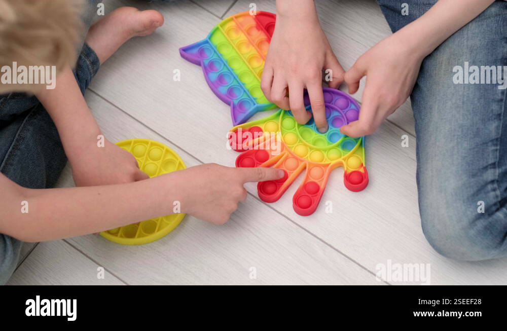 Kids playing with pop it sensory toy. boy and girl pressing on colorful ...