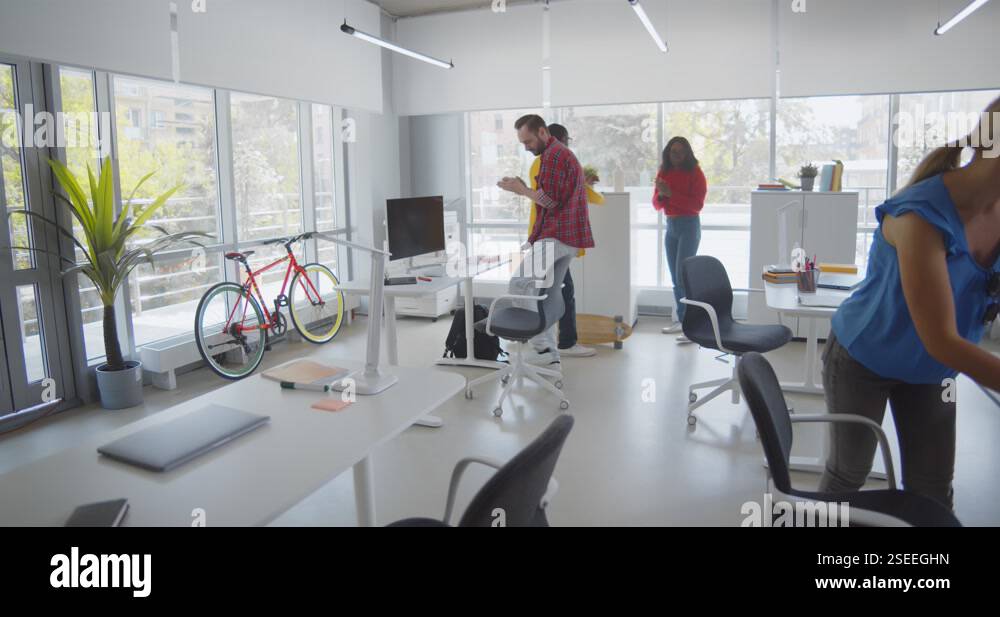 Diverse employees in casual wear sitting down at workplaces in open ...