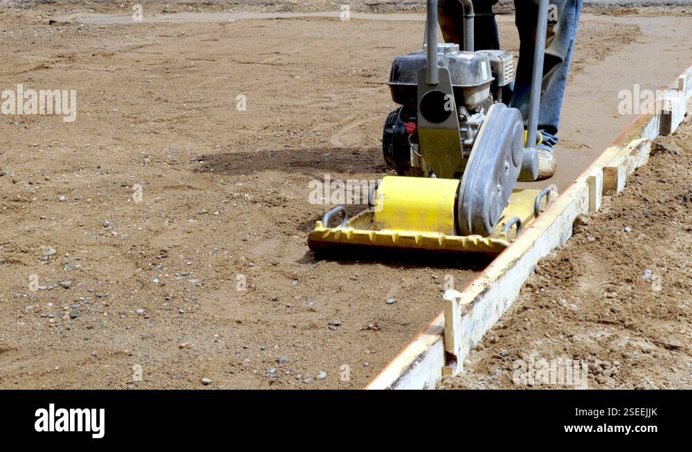 Small yellow compactor used on dirt before concrete is poured on ...