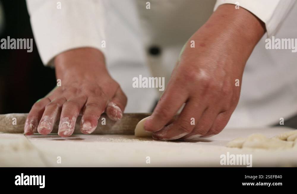 Rolling the round edge of a dumpling with a wooden pin - side view chef ...