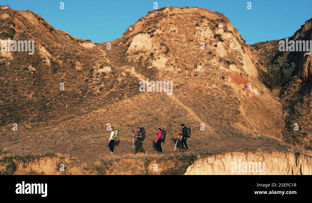 The four people with backpacks are hiking in the sandy mountains Stock ...