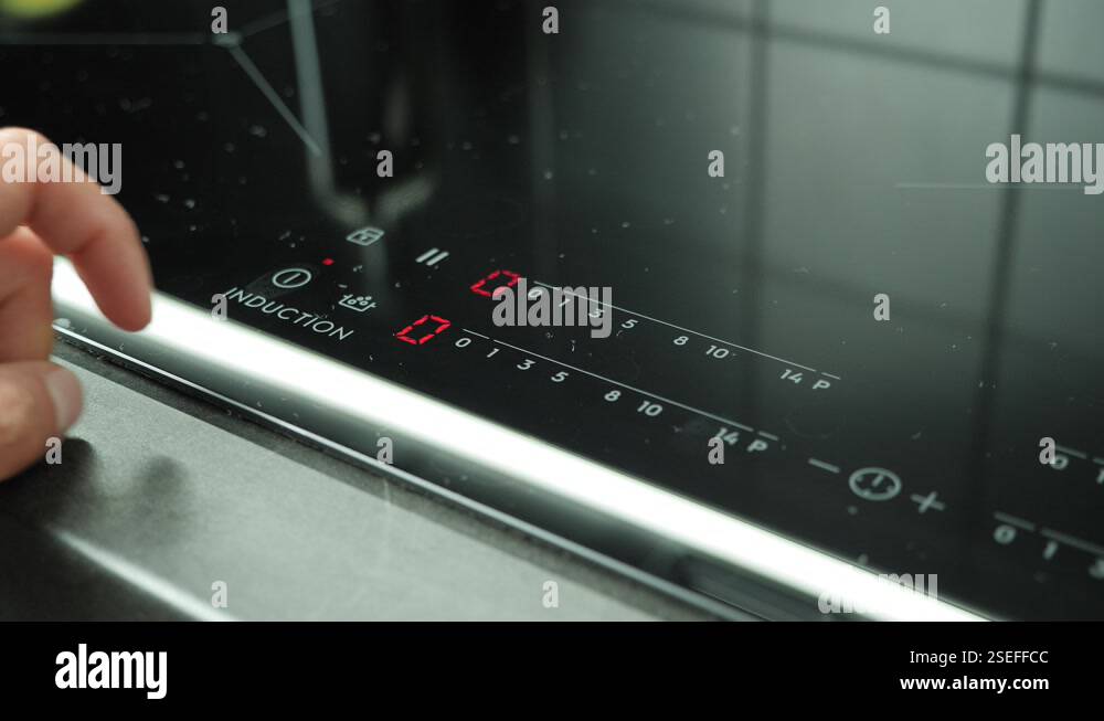 Finger presses electronic touch start button on hob. Induction stove ...