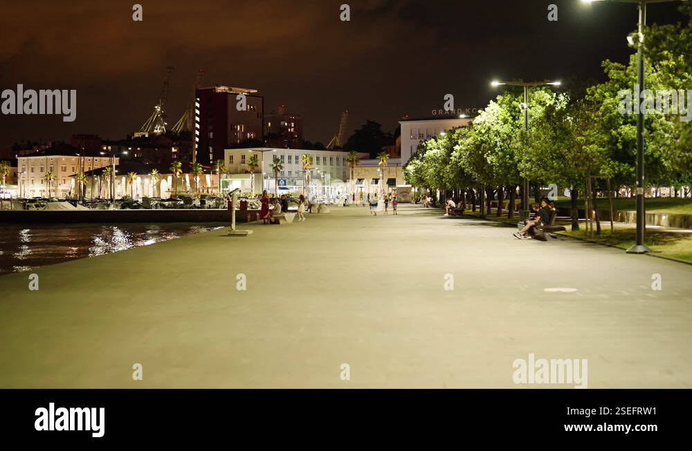 Promenade walk towards the city of Koper at night with lightning storm ...