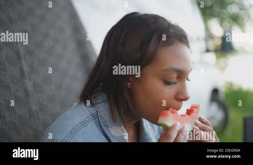 Portrait of an African female in nature, a young woman eating a ...