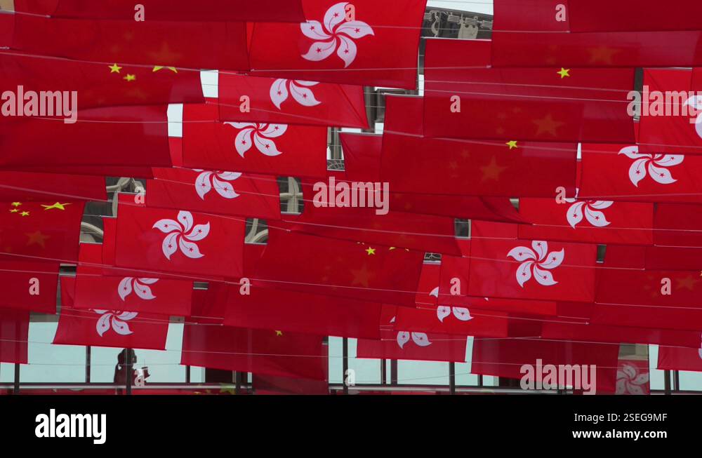 Commuters walk through a pedestrian bridge as flags of the People's ...