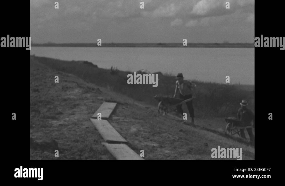 1940s: A group of determined men, their muscles straining, trudge along ...