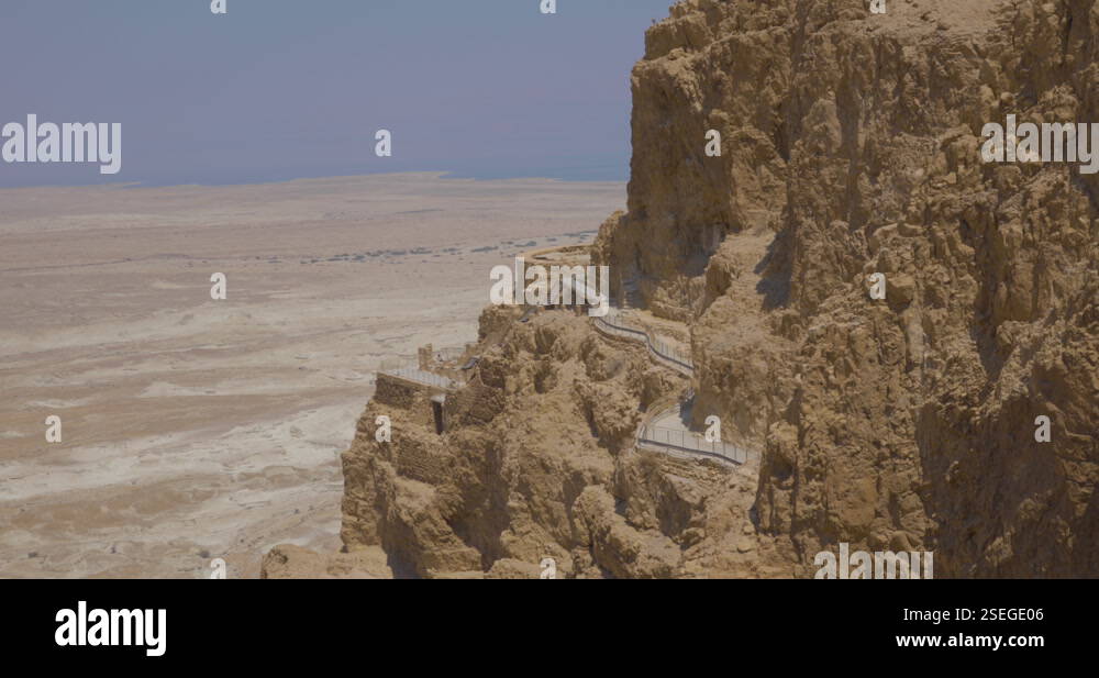 Arid desert landscape and rocky cliff face of Masada fortification in ...