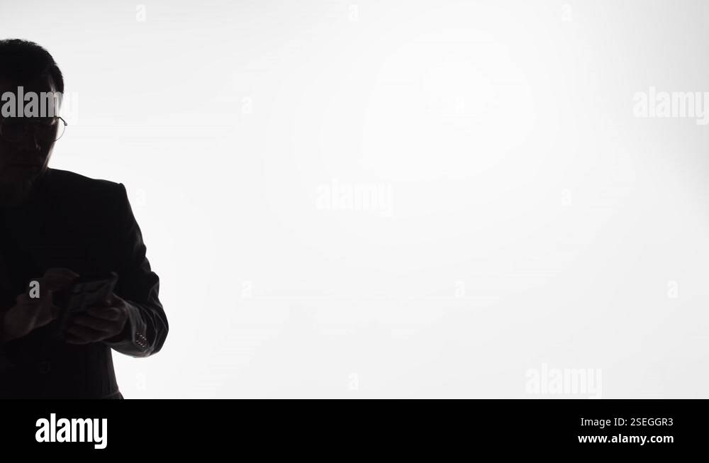 Silhouette of a man with a smartphone pacing back and forth as he works ...