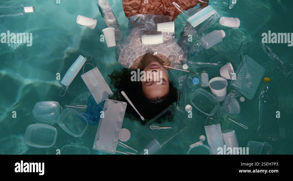 The problem of plastic waste. Cinematic top view young woman lies on ...