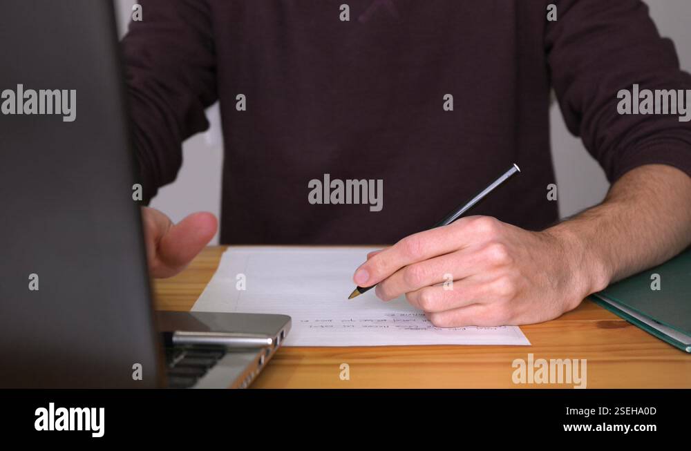 Man Writing On A Blank Paper In Front Of The Laptop On His Work Desk ...