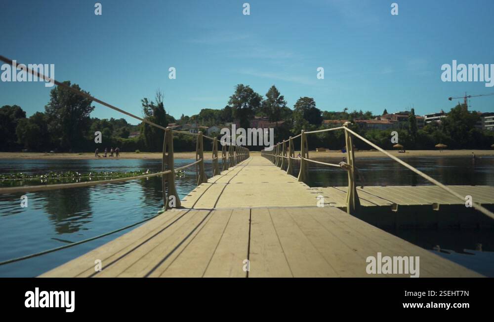 walkway over a river going to a beach with trees. footage moving ...