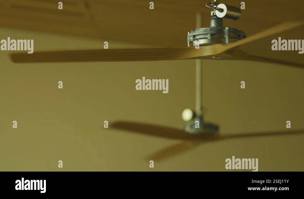 Ceiling fan spinning slowly in sync in a old room with the motor and ...