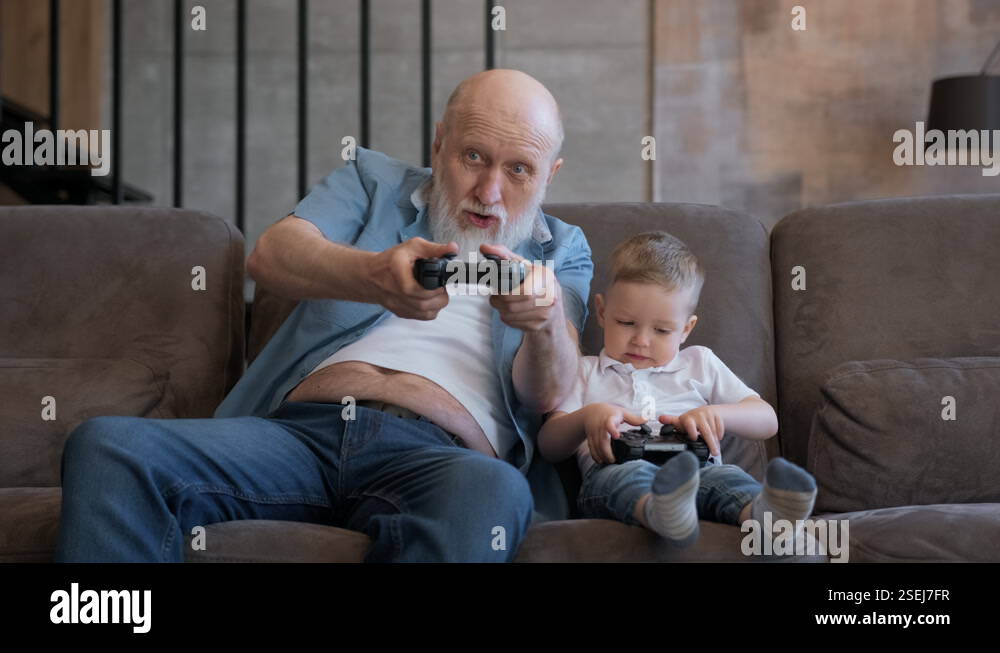 Happy family grandfather plays video game with his boy grandson at home ...