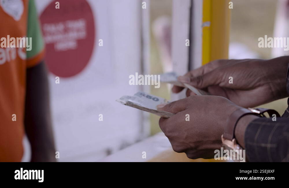 Hands of a mobile money customer counting out cash money notes and ...