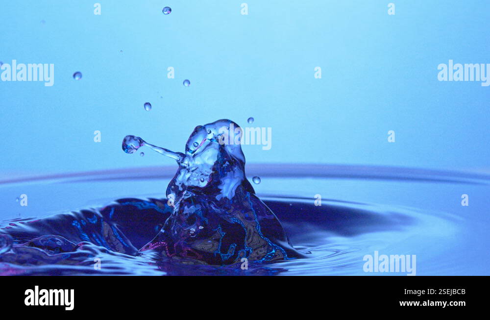 Close up of a thrown ice cube that splashes through purple water ...