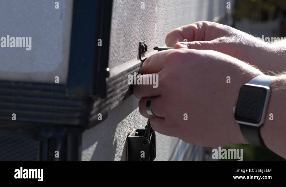 A close up of locking the tent trailer with the clasp on the side to ...