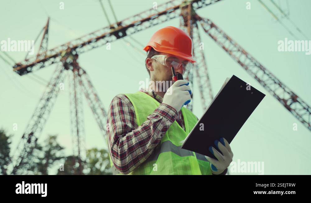 Electrical engineer wearing hard hat and safety vest checking ...