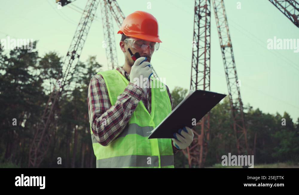 Electrical engineer wearing hard hat and safety vest checking ...