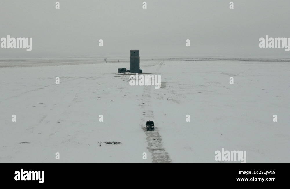Aerial following UTV side by side through snow covered field in winter ...