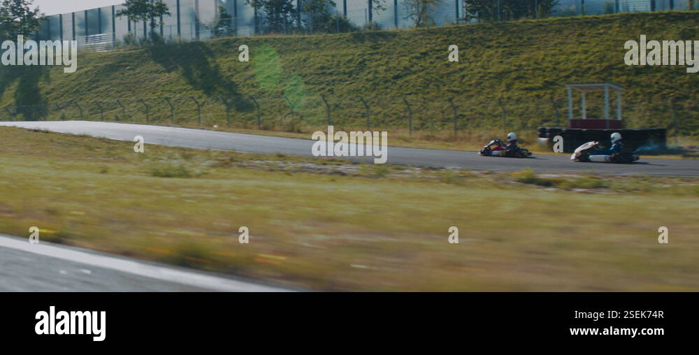 TRACKING Two teenagers pro racers driving their karts on a race track ...