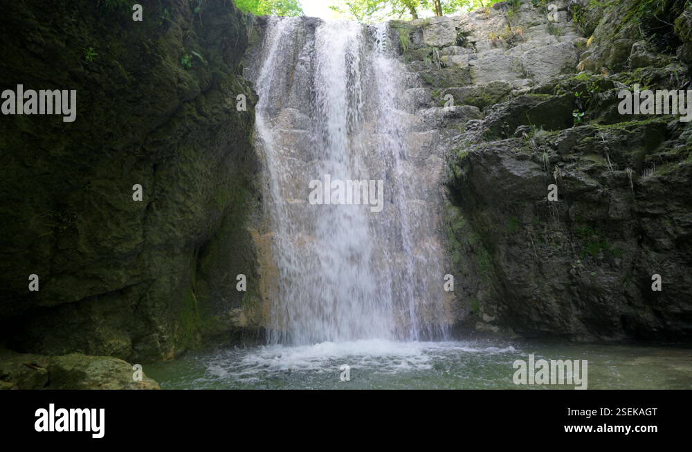 Majestic tropical jungle waterfall crashing down into cave in slow ...