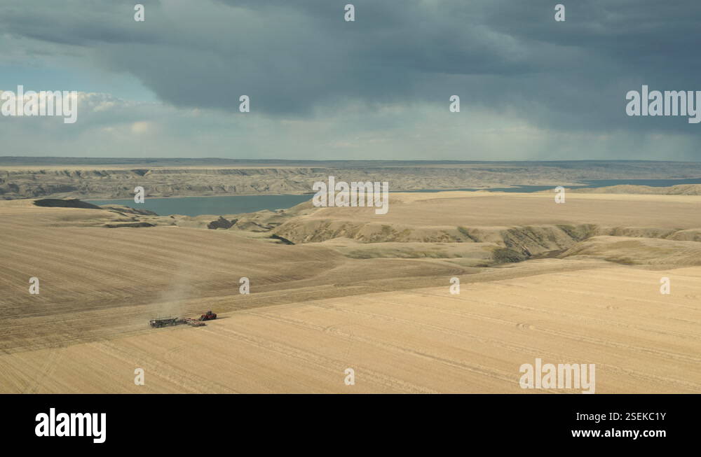 Scenic view of Agricultural tractor sowing seeds in vast field-aerial ...
