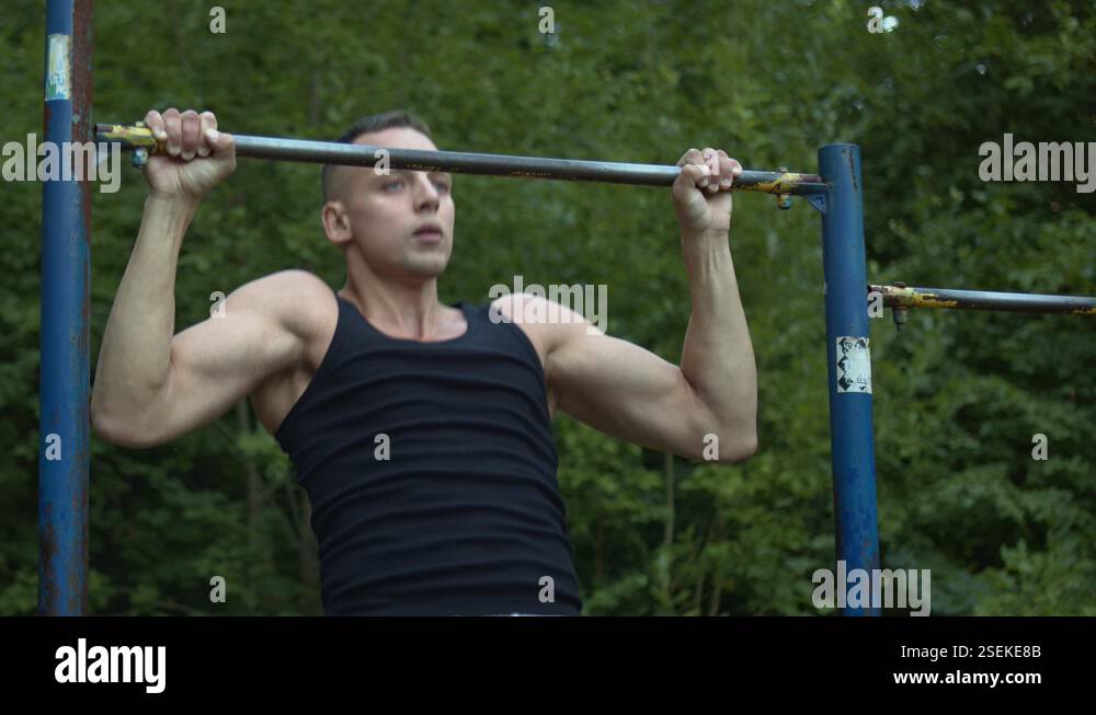 Athletically built man pulls up on the horizontal bar. Loads on ...