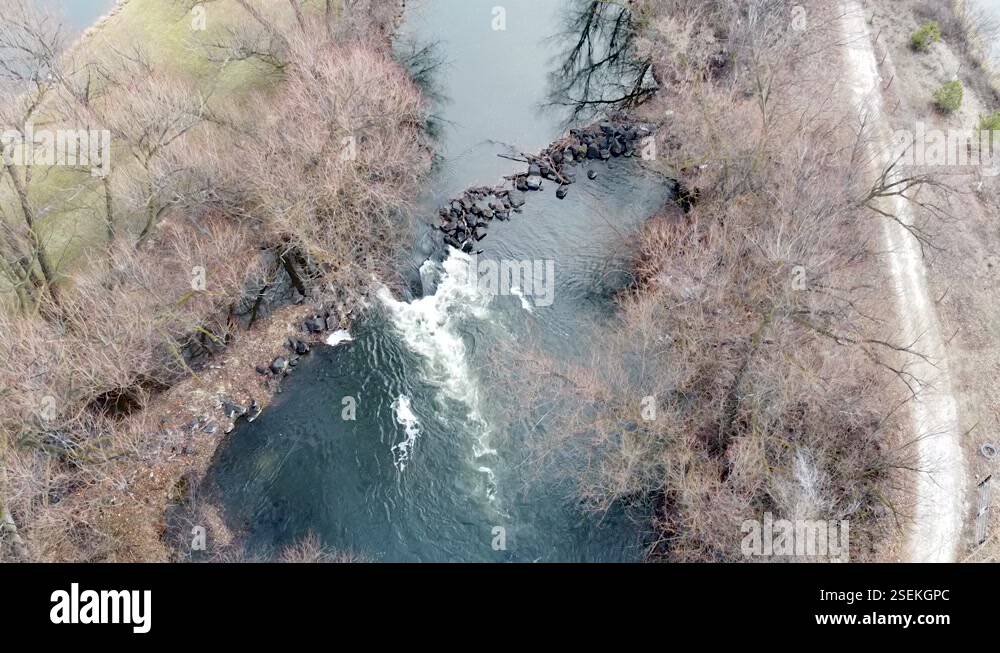 Small river dam and rapids on scenic, idyllic, willow tree lined river ...