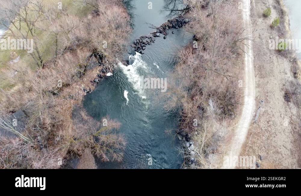Small river dam and rapids on scenic, idyllic, willow tree lined river ...