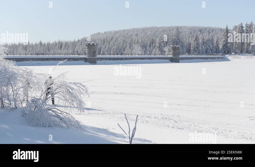 Two cross-country skiers walk along the shore of a frozen lake - a dam ...