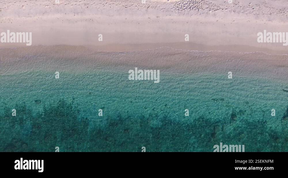 Hovering Aerial of White Sand Beach with Clear Blue Water into Reveal ...