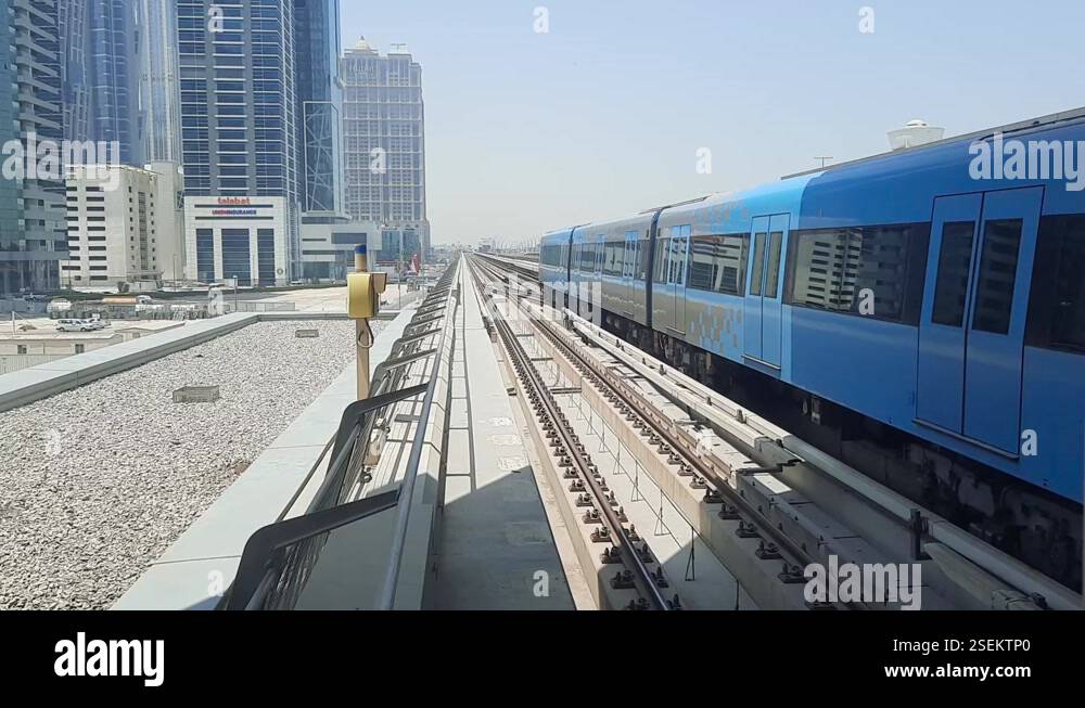 Metro train leaving the station, moving forward in a straight rail ...
