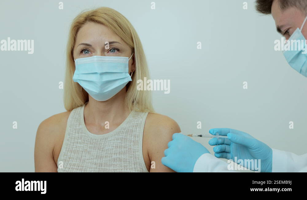 Doctor doing vaccine injection to a female patient in a health clinic ...
