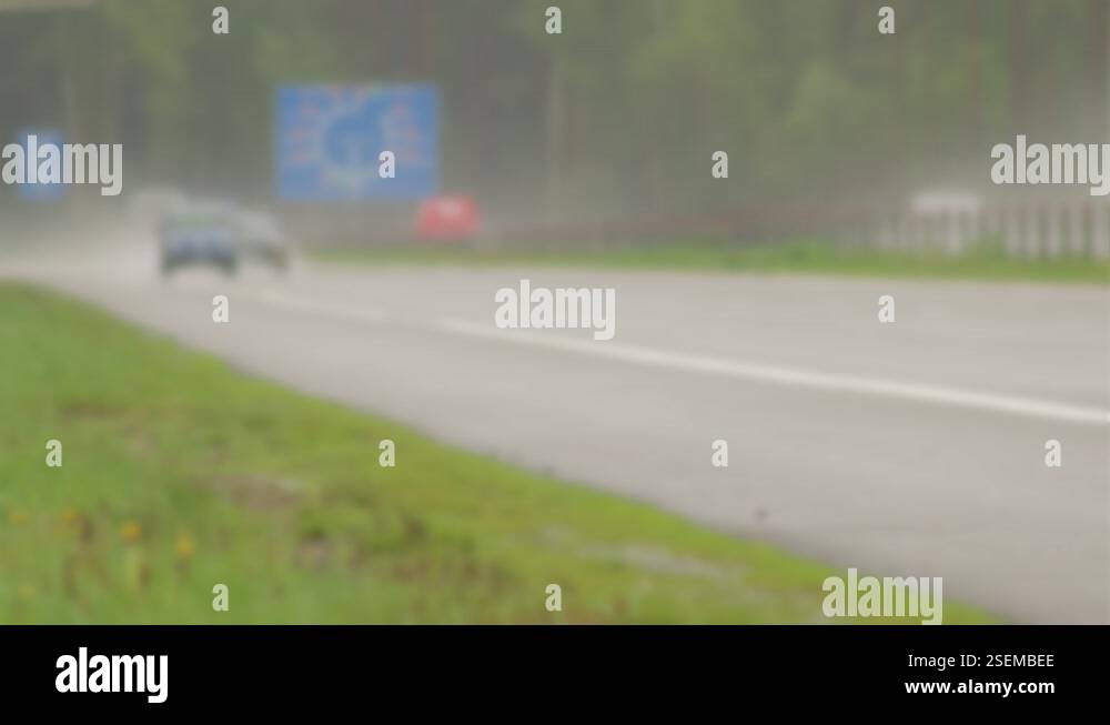 Many cars and trucks with headlights drive on a wet highway in bad ...