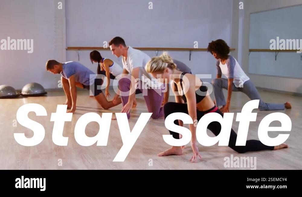 Stay safe text against group of people practicing yoga at the studio ...