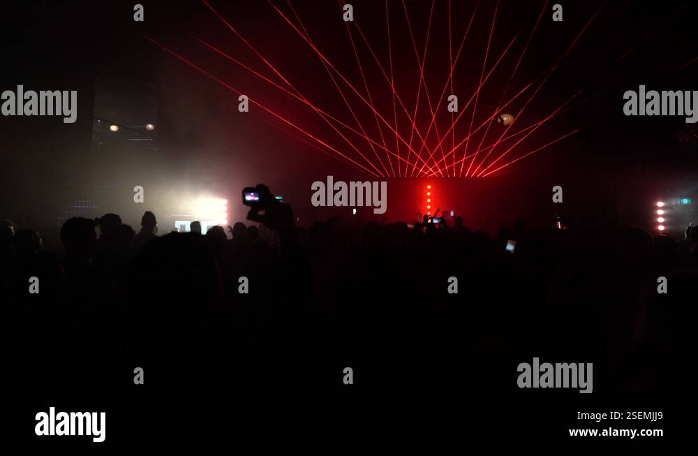 Flashing lights and lasers and people crowd at night club, back view ...